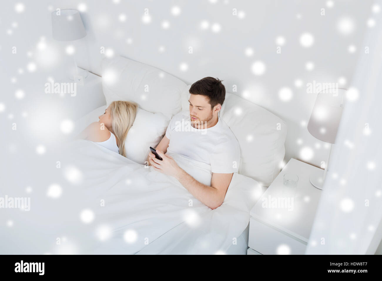 man texting message while woman is sleeping in bed Stock Photo - Alamy