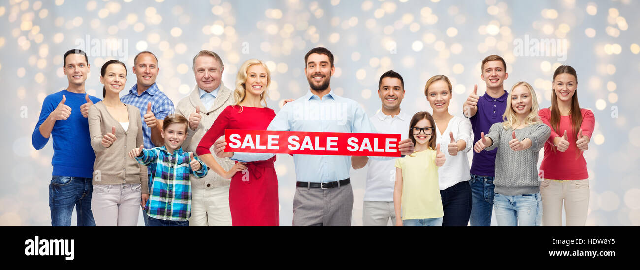 happy people with sale sign showing thumbs up Stock Photo - Alamy