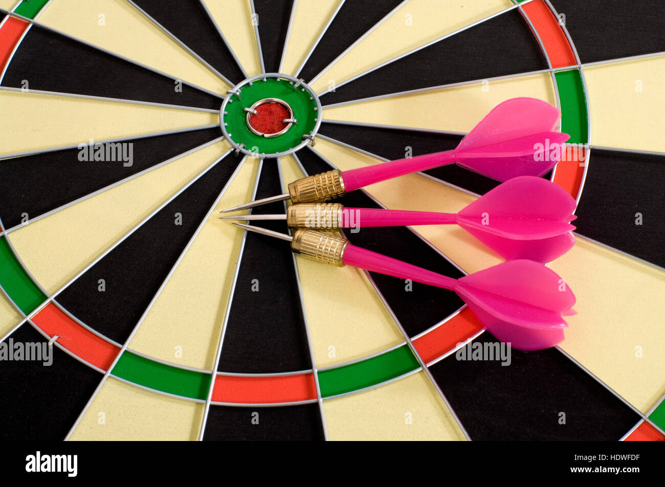Three pink darts and circular dart board Stock Photo - Alamy