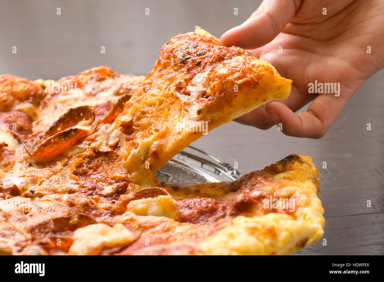 A Hand take a slice of pizza from the pan Stock Photo - Alamy