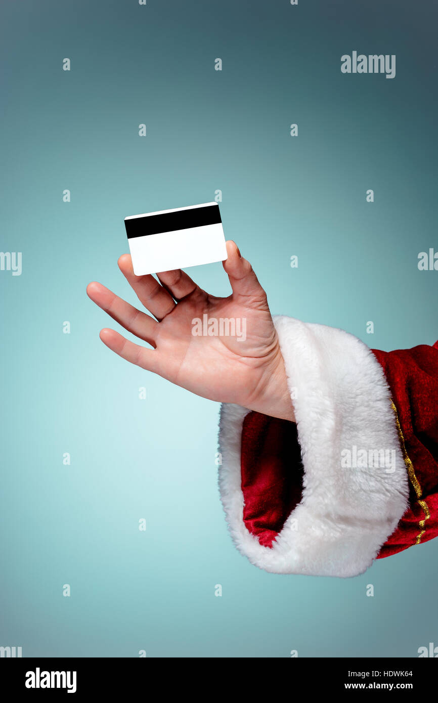 Santa Claus hand holding a credit card on blue studio background Stock ...