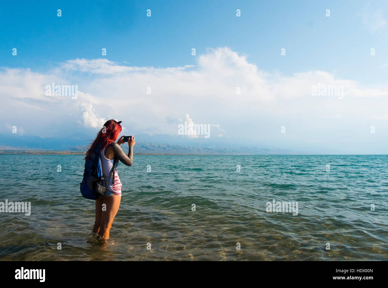 Caucasian woman wading in ocean photographing with cell phone Stock ...