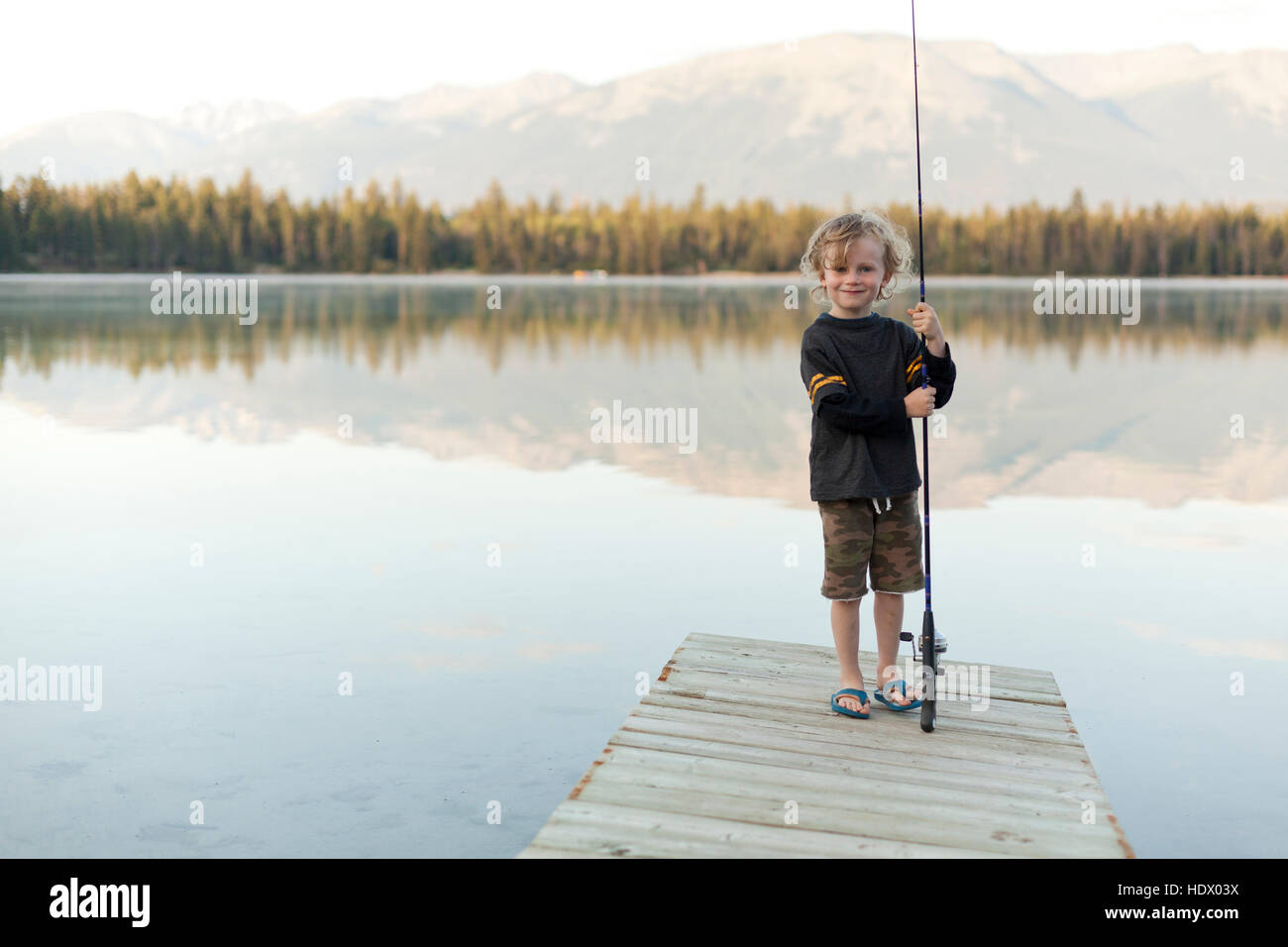 Caucasian boy standing on dock at lake holding fishing rod Stock Photo ...