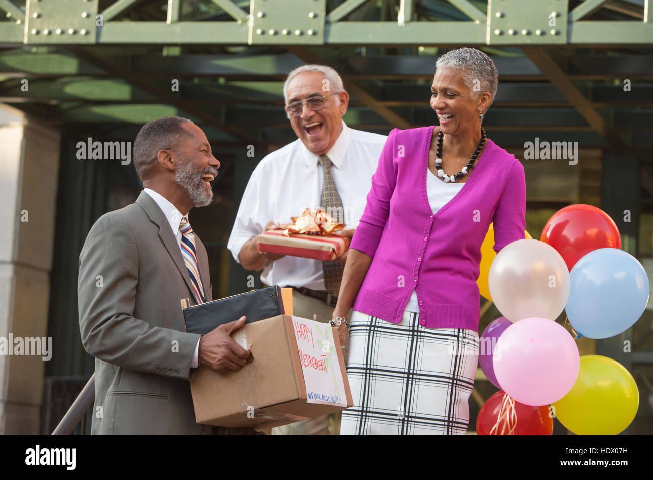 Co-workers celebrating with retiring man carrying belongings Stock ...