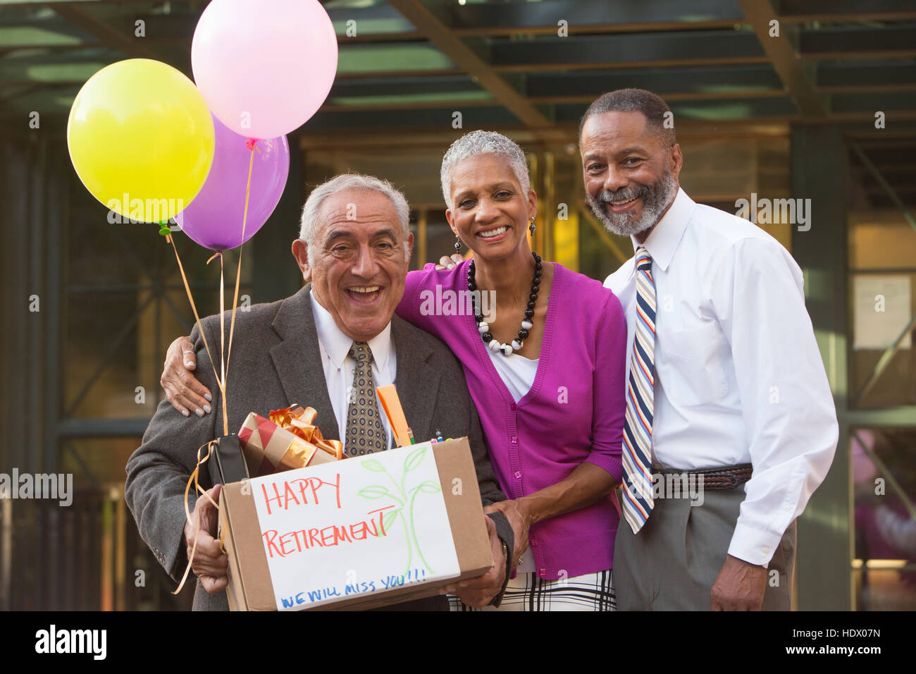 Co-workers posing with retiring man carrying belongings Stock Photo - Alamy