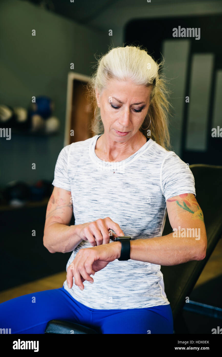 Caucasian woman tapping smart watch in gymnasium Stock Photo - Alamy