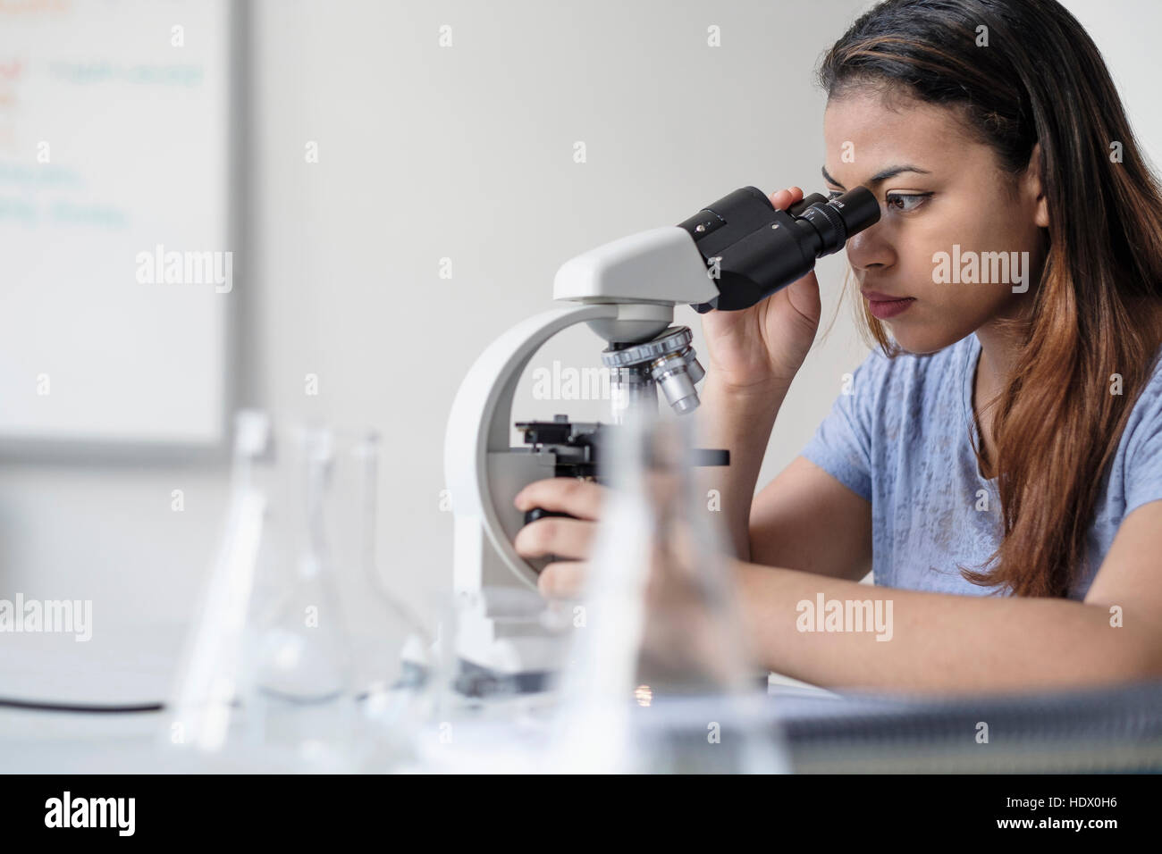 Hispanic woman using microscope Stock Photo - Alamy