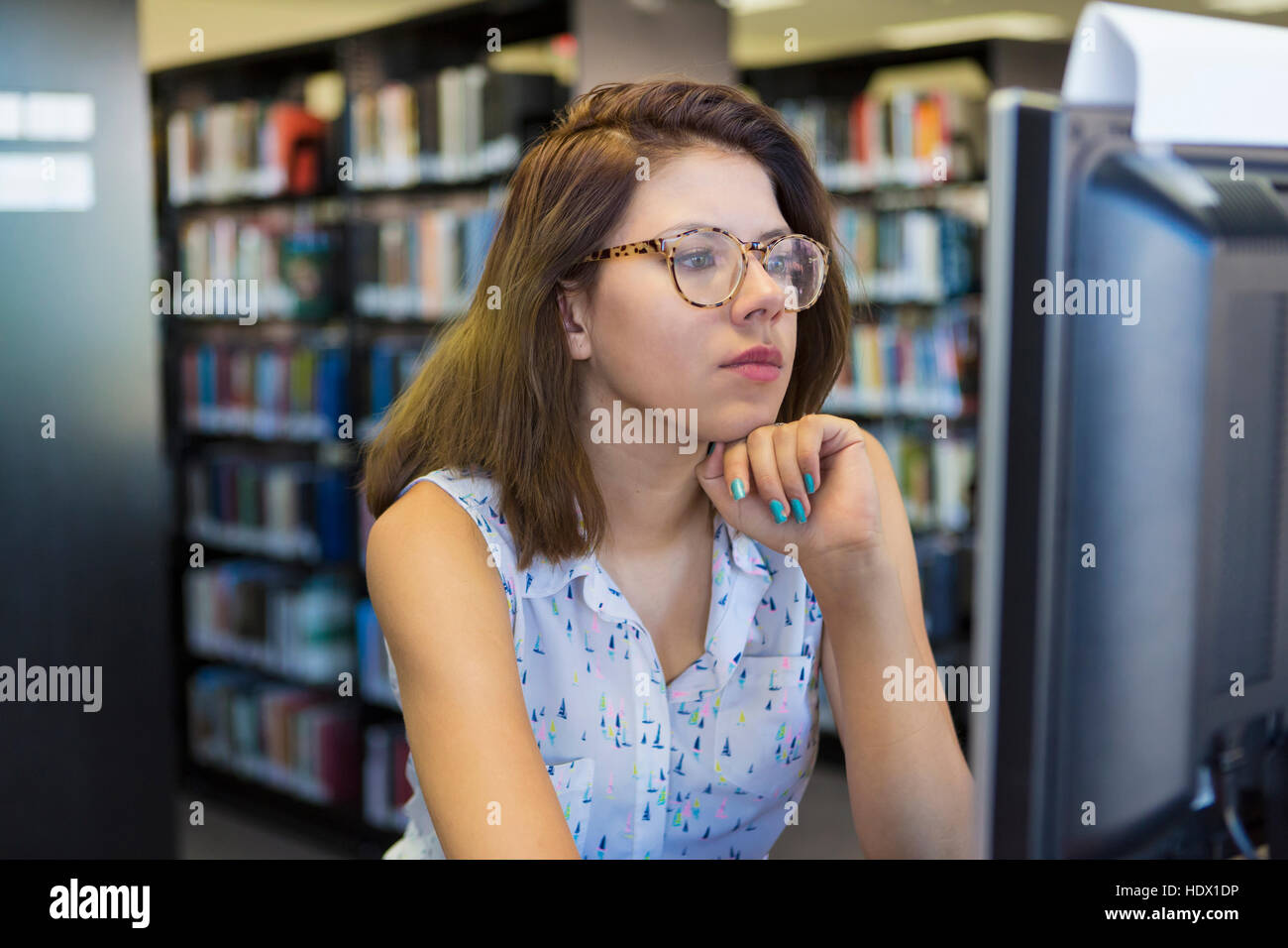 Mixed Race girl using computer in library Stock Photo - Alamy