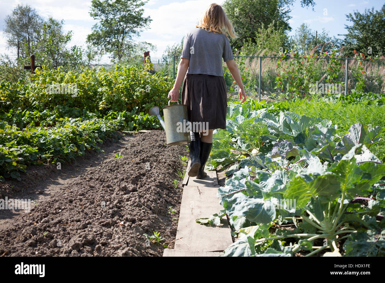 Caucasian woman carrying watering can in garden Stock Photo - Alamy
