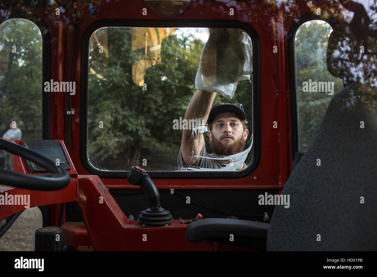 Caucasian man washing window of tractor Stock Photo - Alamy