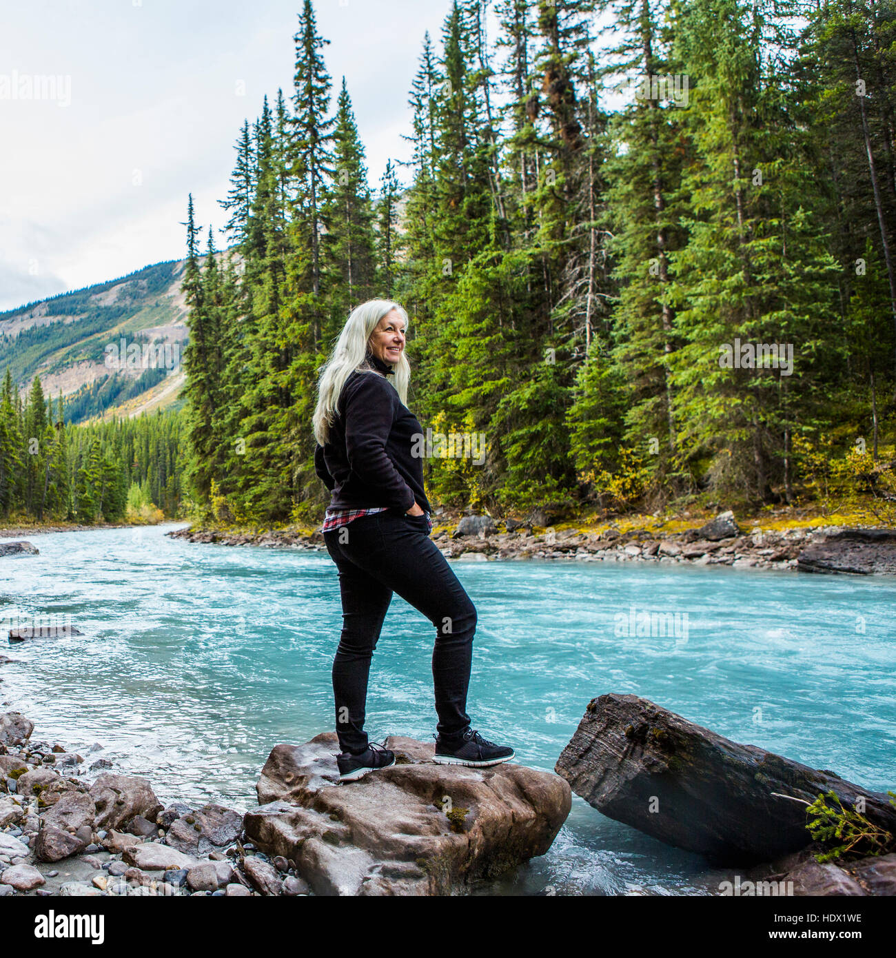 Caucasian woman standing on rock near mountain river Stock Photo - Alamy