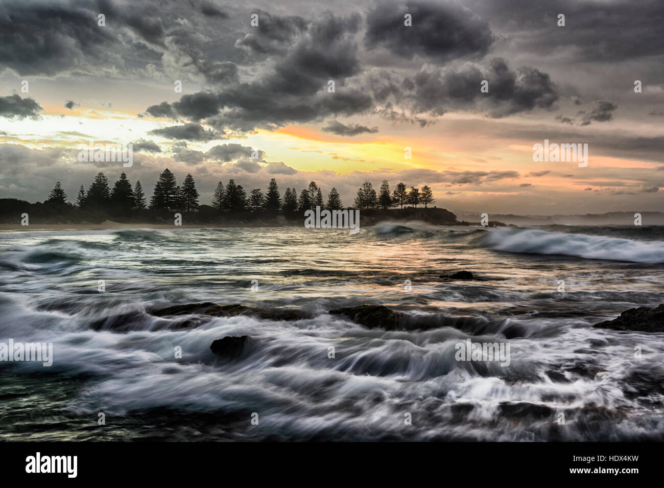 Dramatic atmospheric sunset over large waves on the beach at Bermagui ...