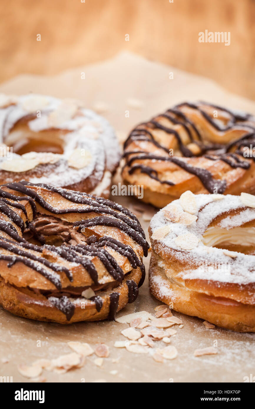 Chocolate and powdered sugar cream puff rings (choux pastry), black and ...