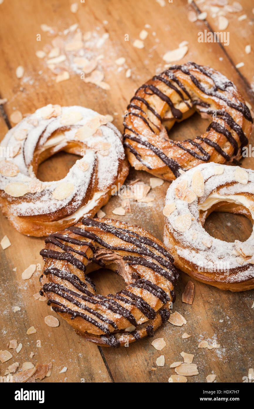 Chocolate and powdered sugar cream puff rings (choux pastry), black and ...