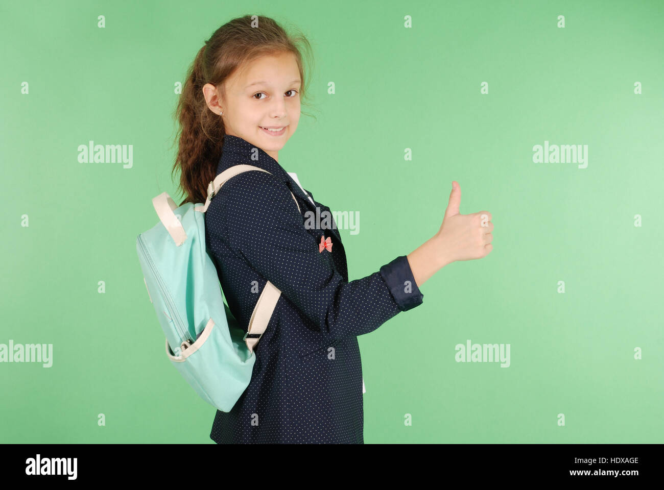 Smiling young school girl showing thumbs up isolated on green ...