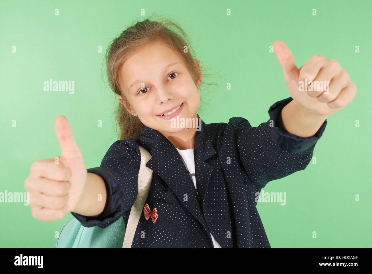 Smiling young school girl showing thumbs up isolated on green ...