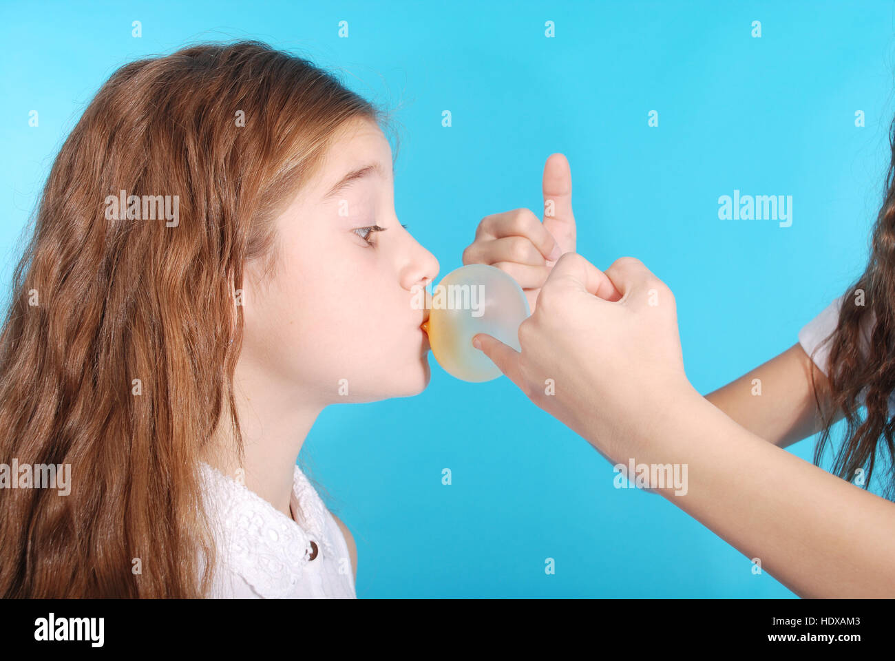 Two young girls playing with chewing gum isolated on blue Stock Photo ...