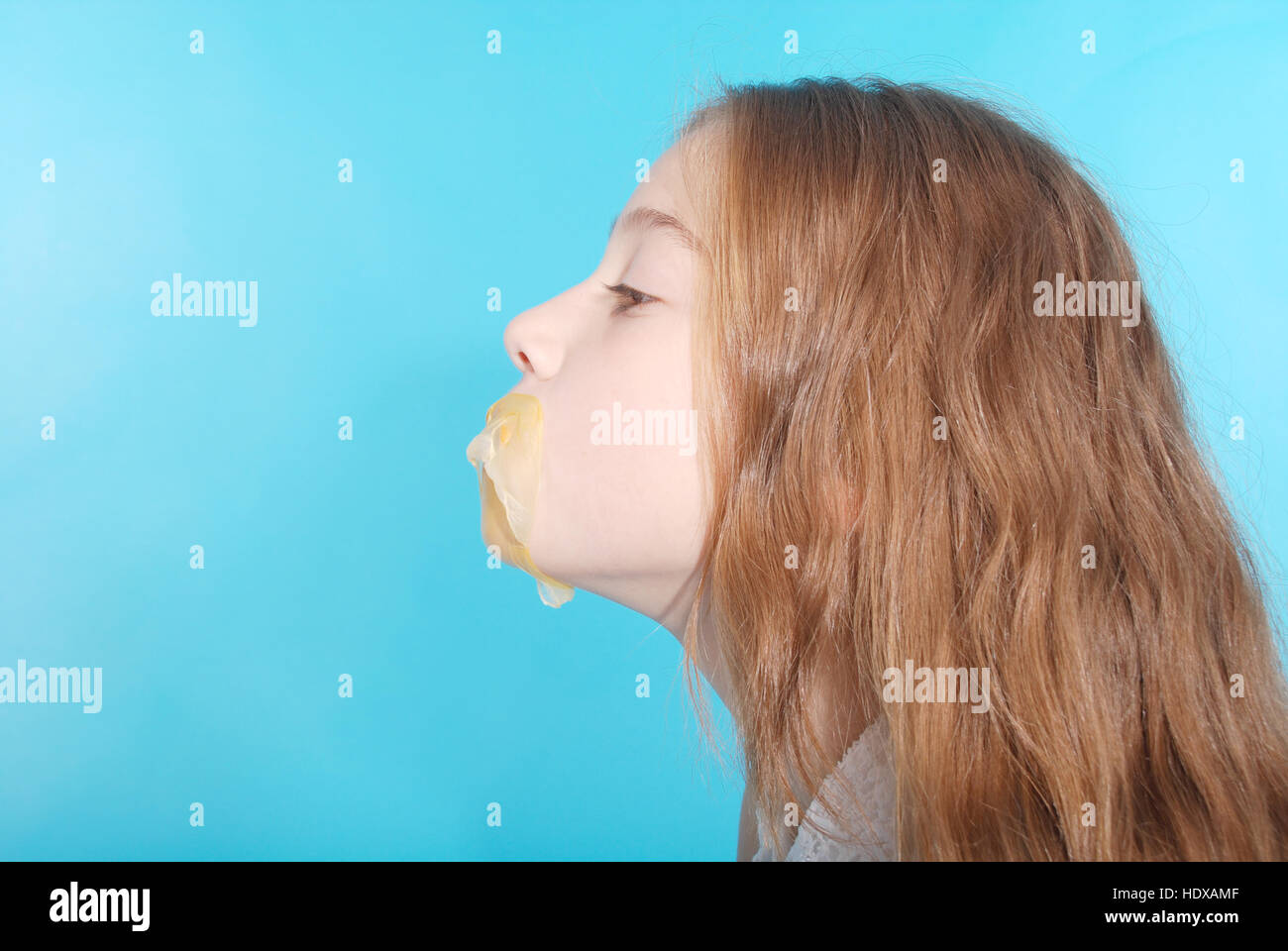 Young girl playing with chewing gum isolated on blue Stock Photo - Alamy