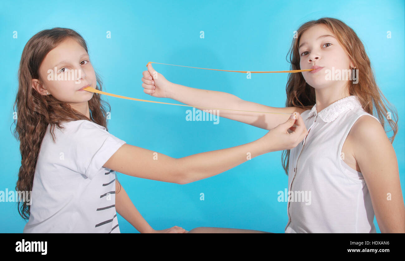 Two young girls playing with chewing gum isolated on blue Stock Photo ...