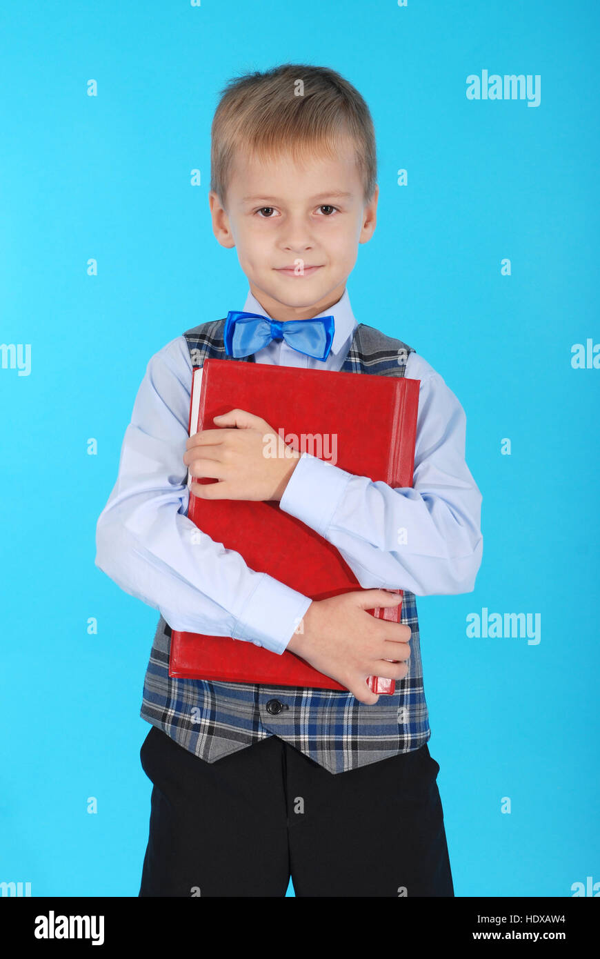 Boy in school uniform holding a red book on a blue background Stock ...