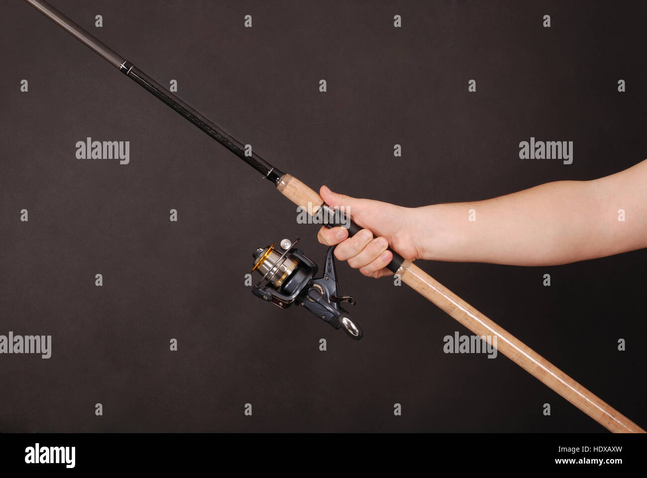 Man's hand holding a fishing rod on a black background Stock Photo - Alamy