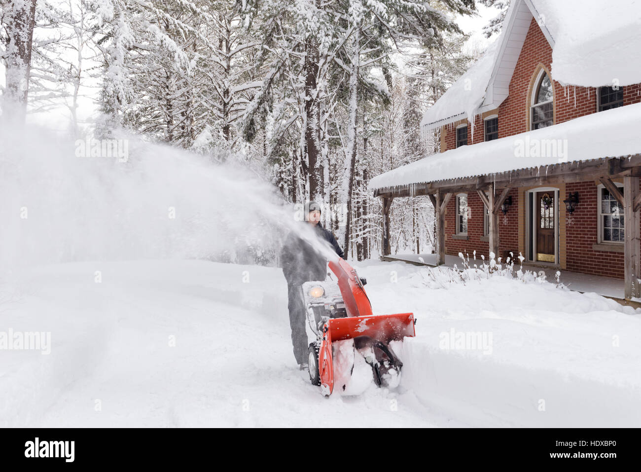 Man with a snow blower clearing a driveway in a beautiful snowy ...