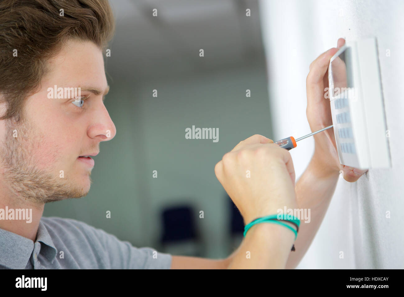 Man with screwdriver fitting panel to wall Stock Photo - Alamy
