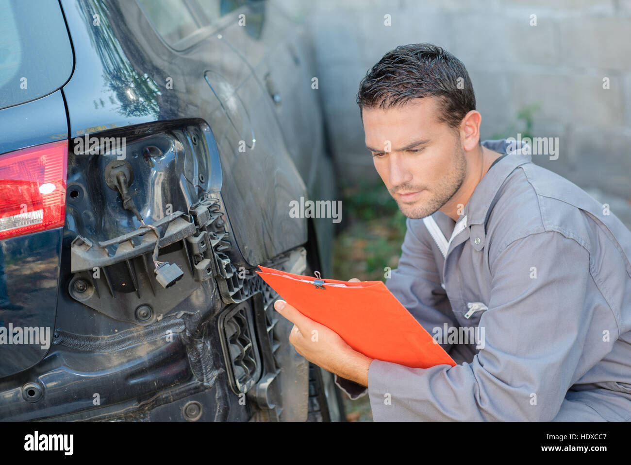 Young mechanic inspecting a damaged car Stock Photo - Alamy
