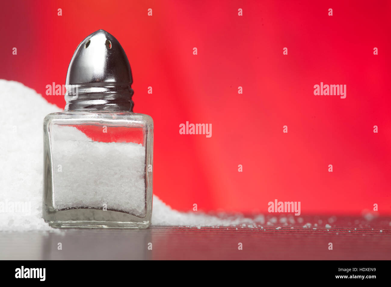 glass salt shaker on gray table and red background for text Stock Photo ...