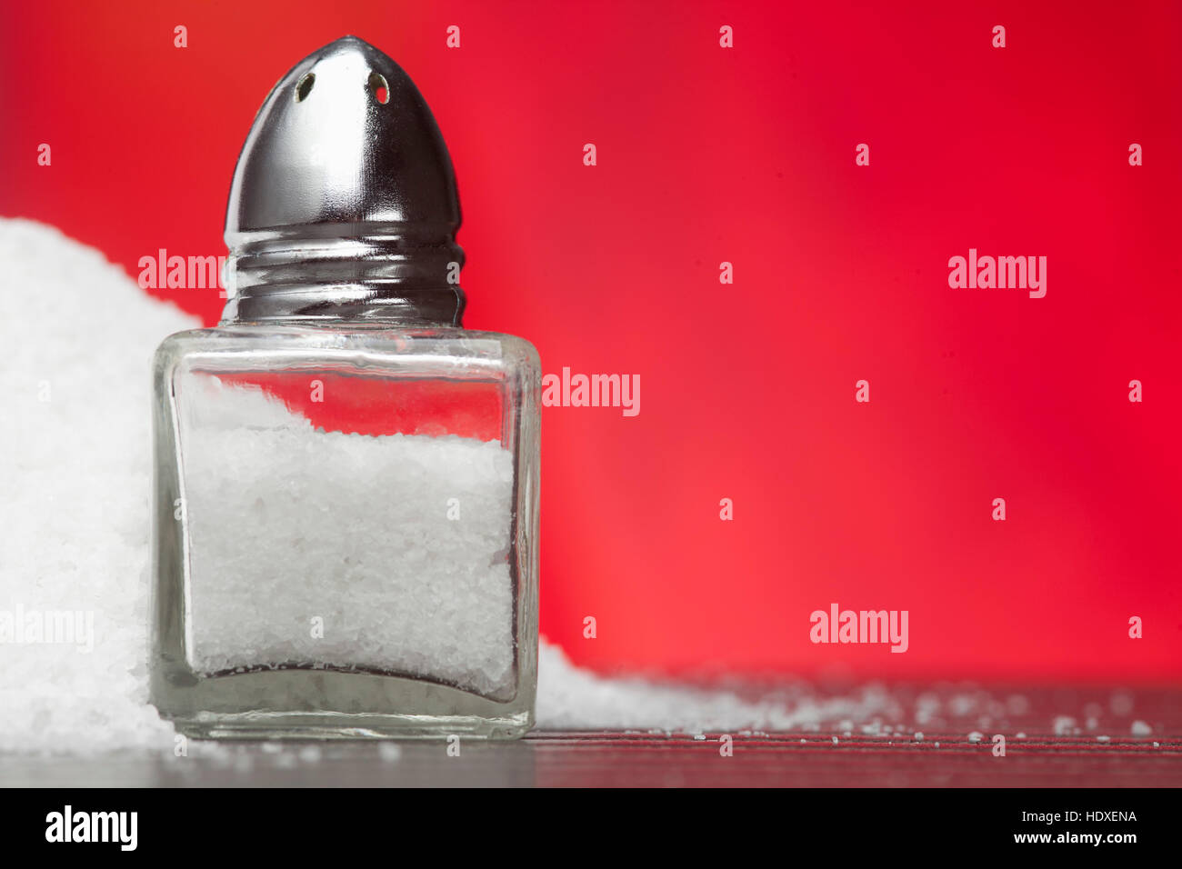 glass salt shaker on gray table and red background for text Stock Photo ...