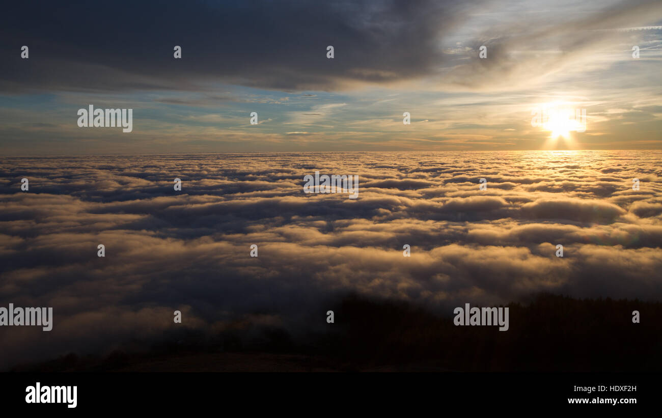 Landscape with the sun setting behind clouds and fog Stock Photo - Alamy