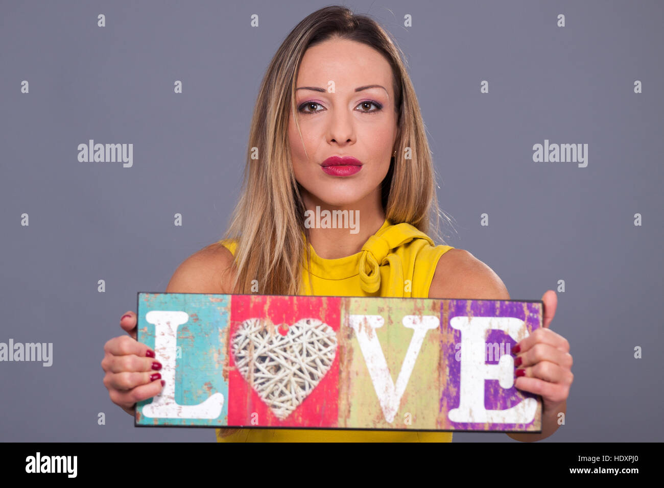 Valentines Day. Woman wearing yellow dress holding sign love symbol on ...