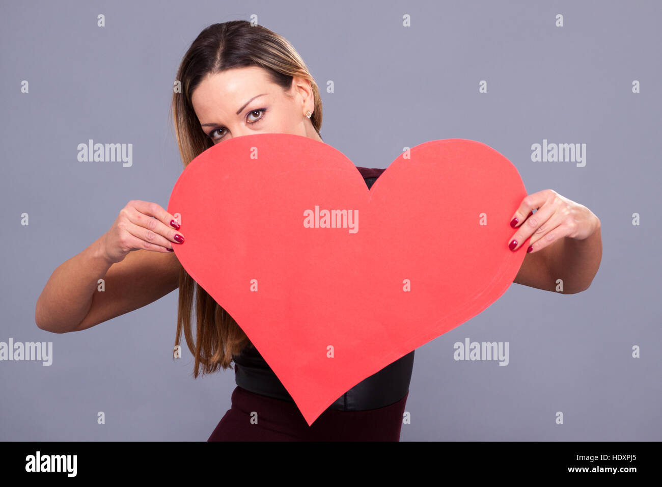 Valentines Day. Woman wearing red dress holding big heart sign love ...