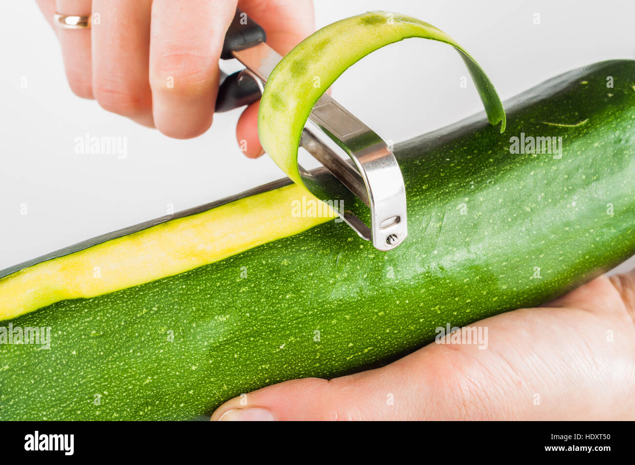 Peeling zucchini with peeler on white background Stock Photo - Alamy