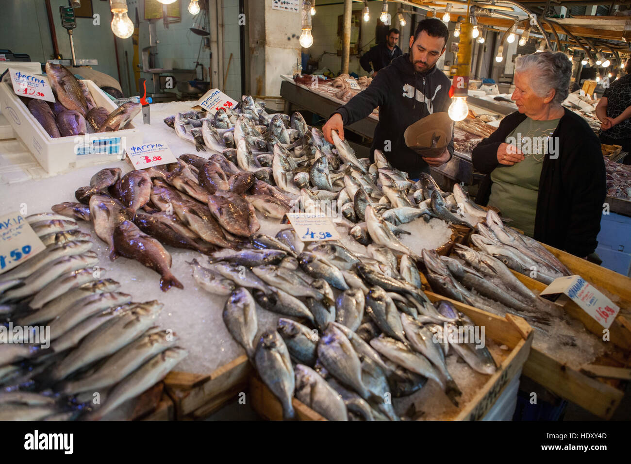 A fishmonger serves a customer in the Central Market in Athens Stock ...