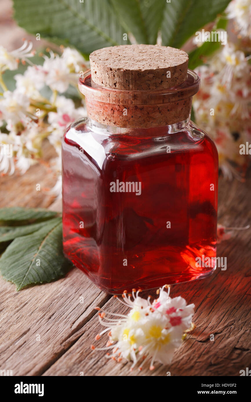 Chestnut tincture of flowers in a bottle on the table. vertical closeup ...