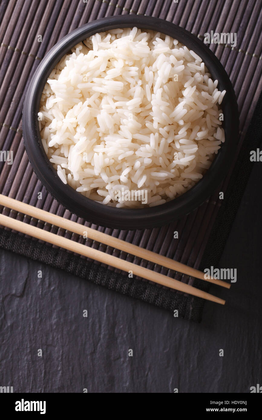 Dietary rice in a black bowl close-up and chopsticks. vertical top view ...