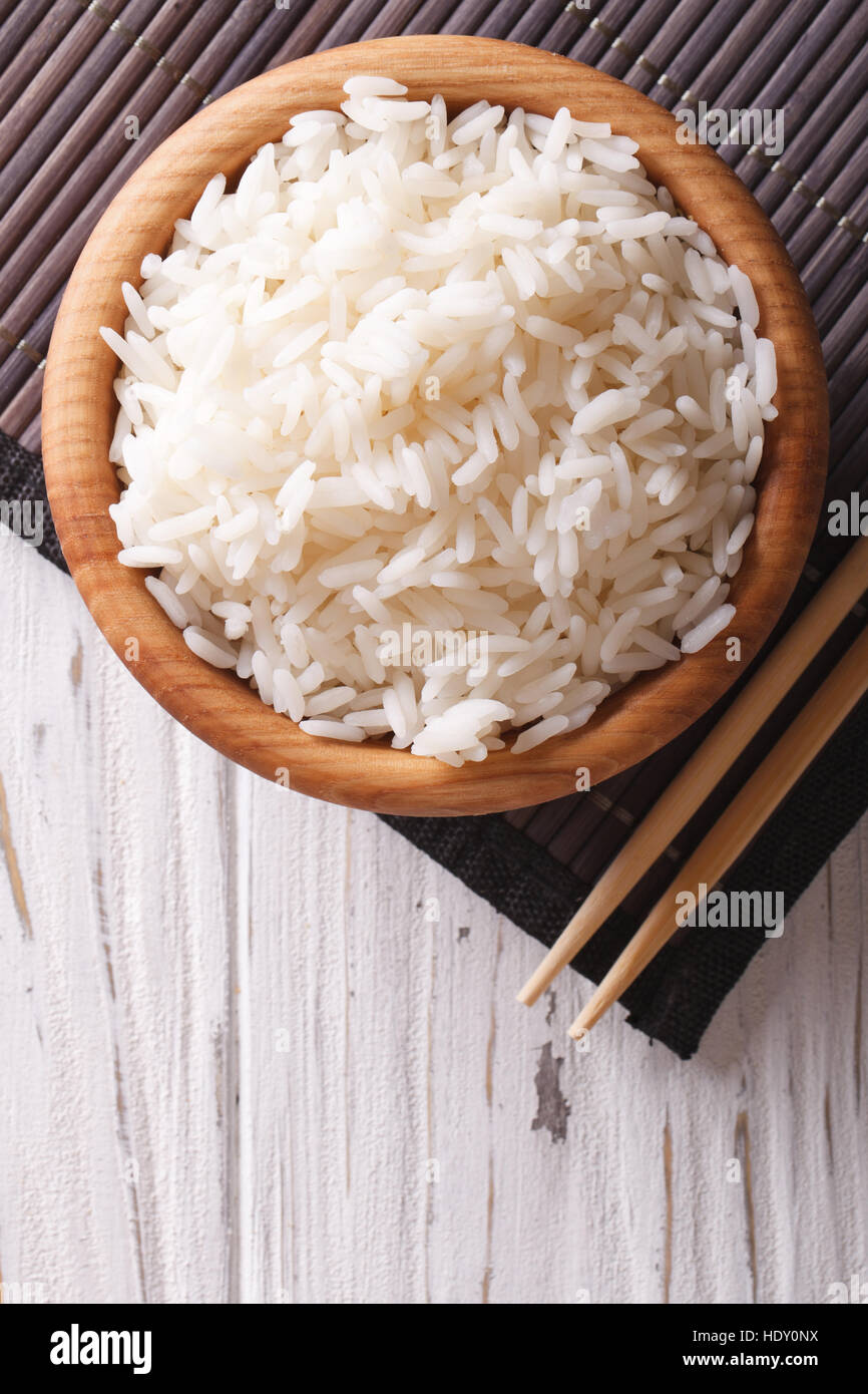 rice in a wooden bowl and chopsticks close-up. vertical top view Stock ...