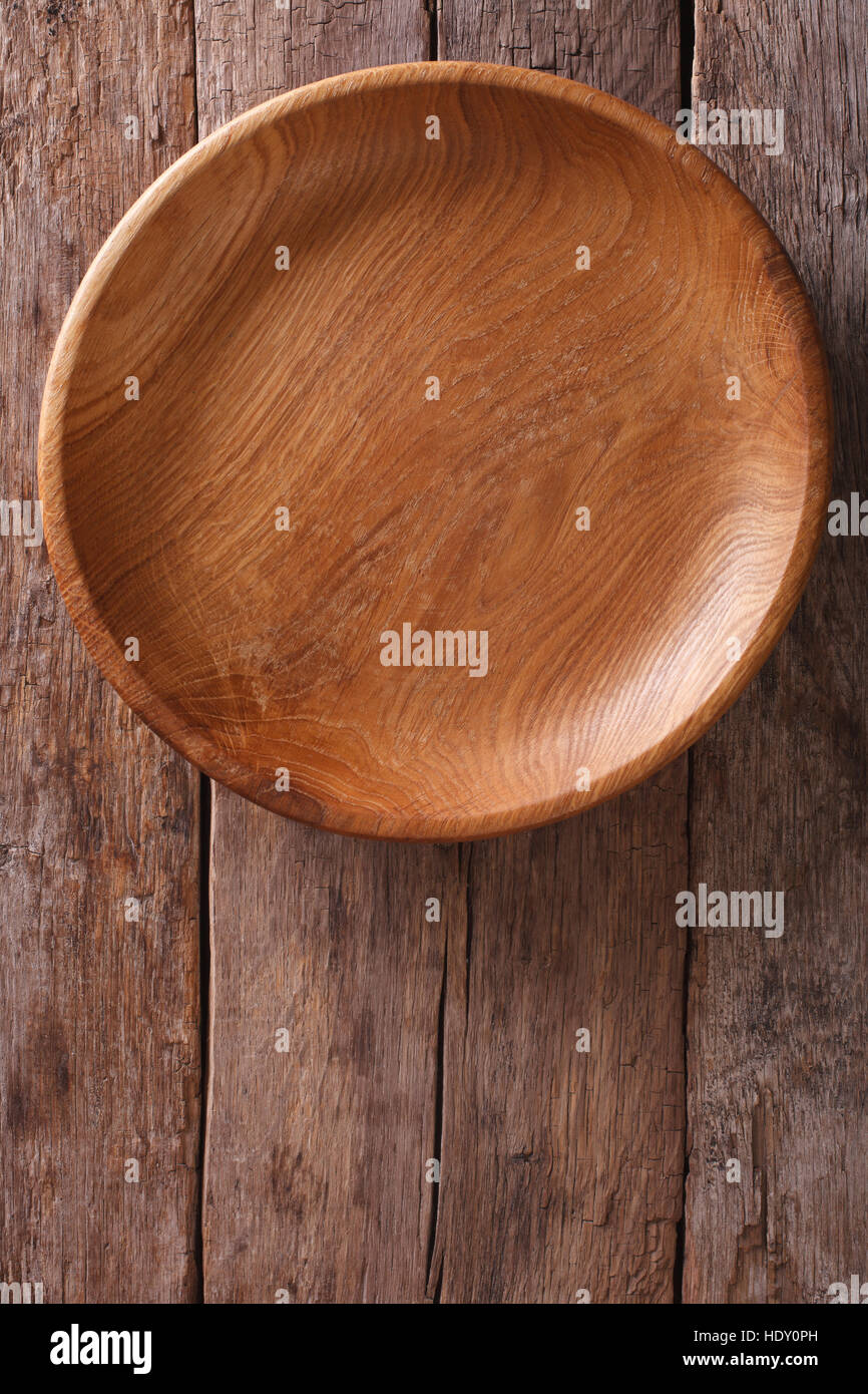 The brown wooden plate on a rustic table closeup. vertical top view ...