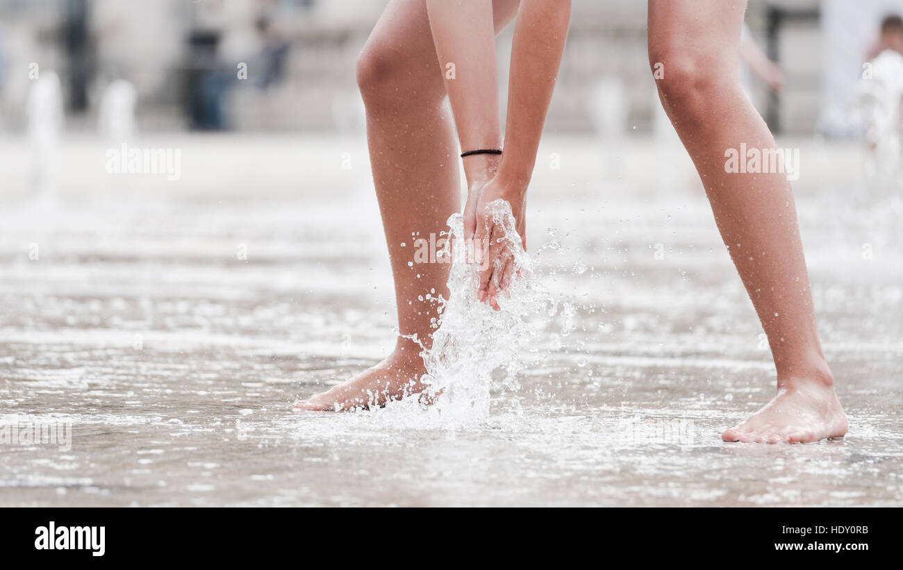 Woman splashing in water in an urban fountain/water installation Stock ...