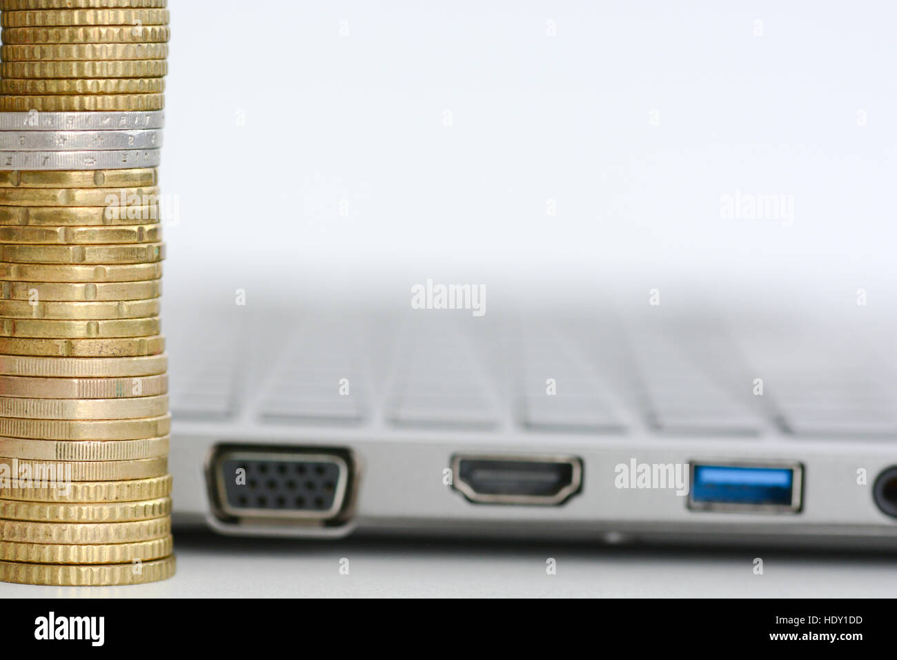 Stack or pile of coins and a laptop keyboard Stock Photo - Alamy