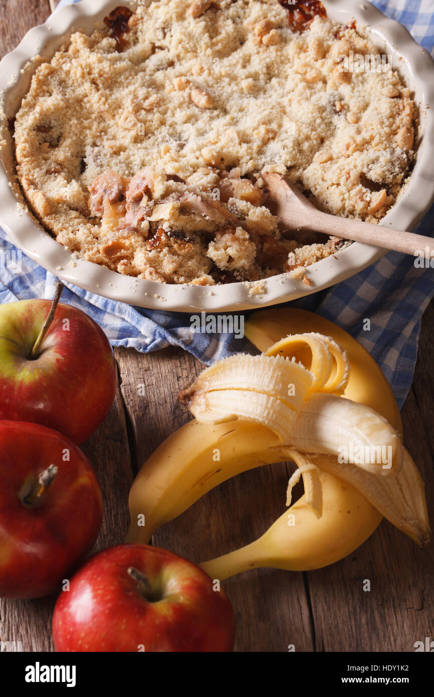 Crumble with apple and banana close-up on the table. vertical, rustic ...