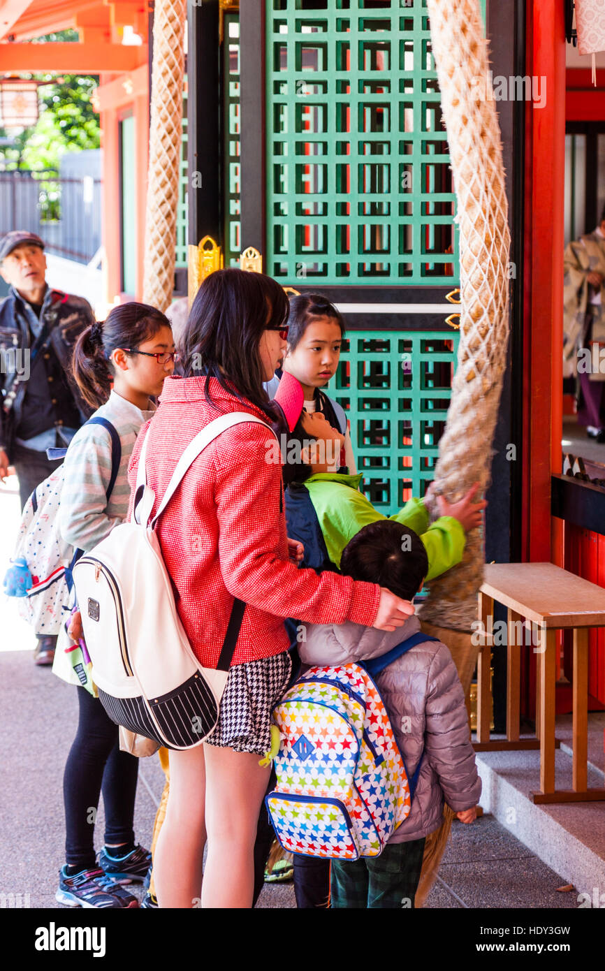 Japan, Kobe, Ikuta Shinto Shrine. Woman and three children shaking bell ...