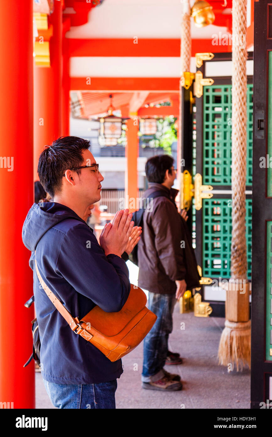 Japan, Kobe, Ikuta Shinto Shrine. Man and woman clapping while praying ...
