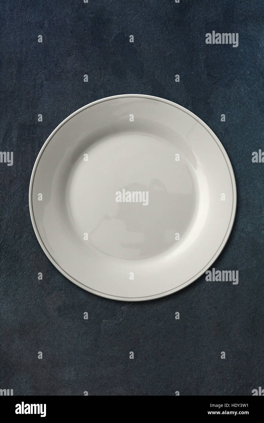 White plate isolated on dark gray slate stone background Stock Photo ...