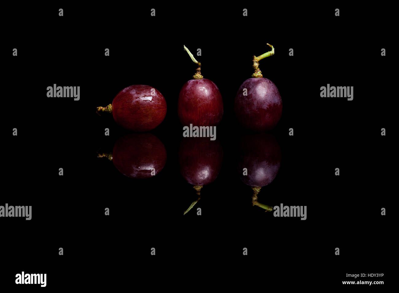 Three red grapes isolated on black reflective background Stock Photo ...