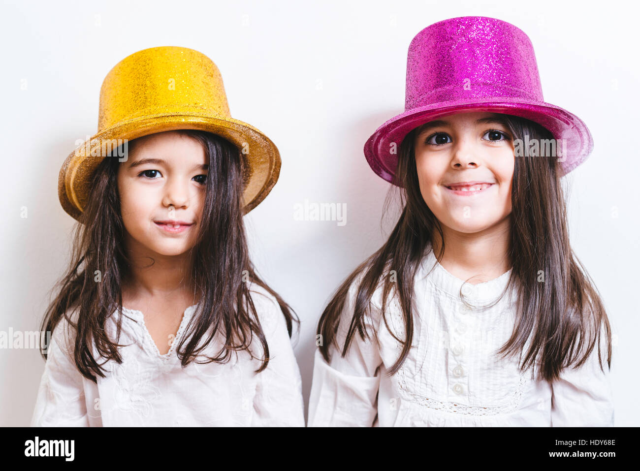 Two girls posing with yellow and pink shiny hats Stock Photo - Alamy