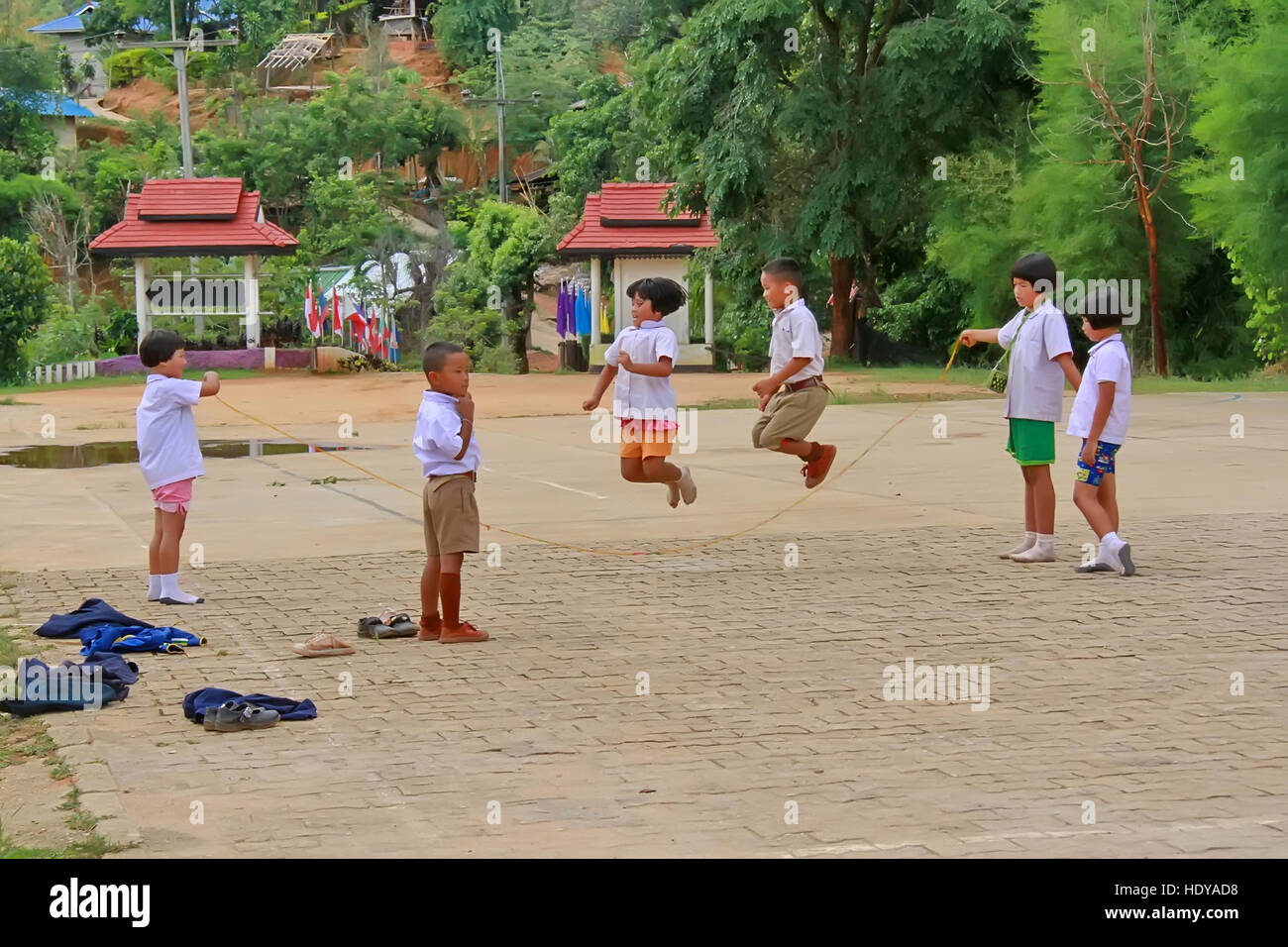 schoolchildren skipping together with jumping rope on countryside ...
