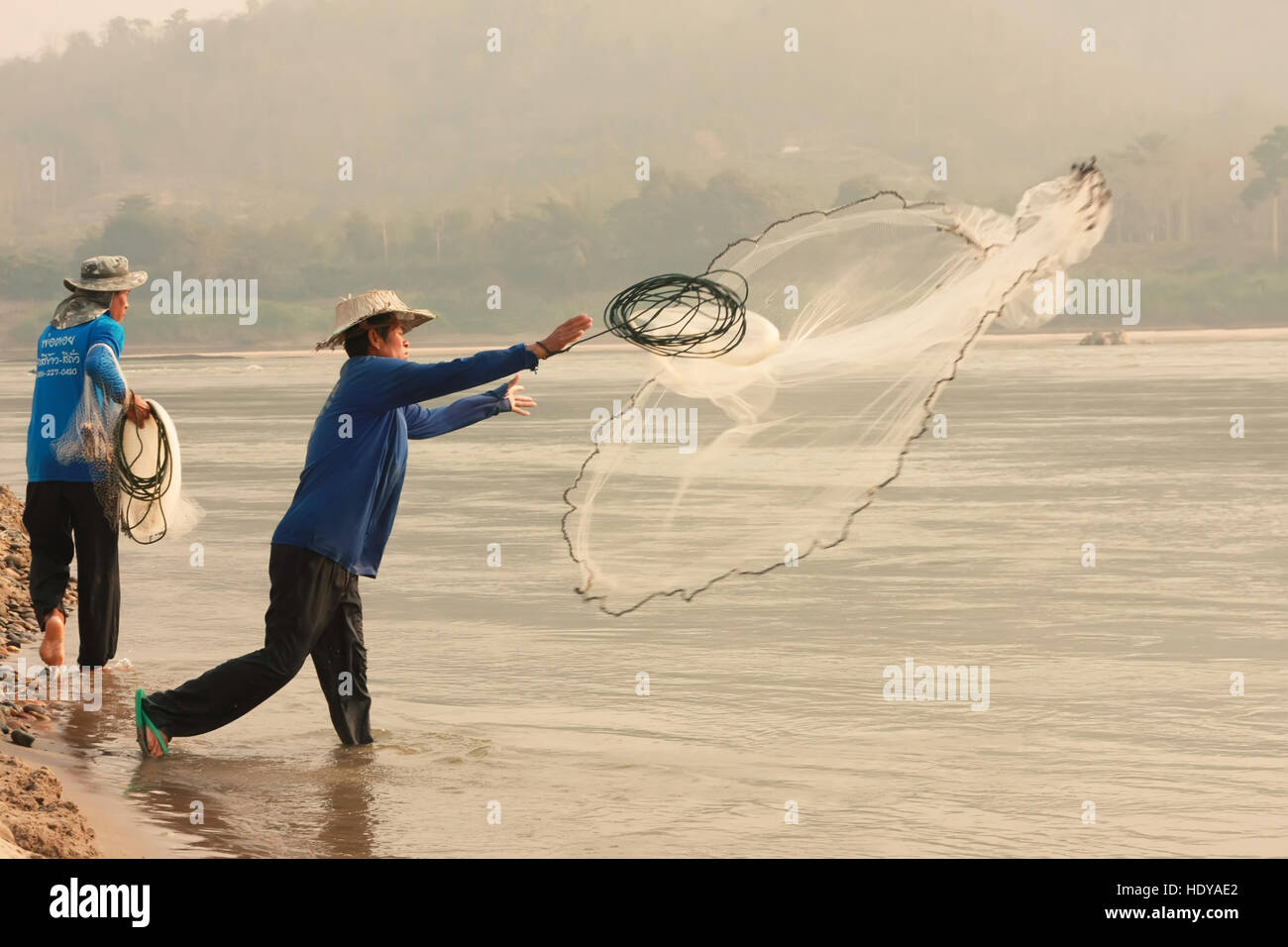 two fisherman throwing fishing net during sunrise Stock Photo - Alamy