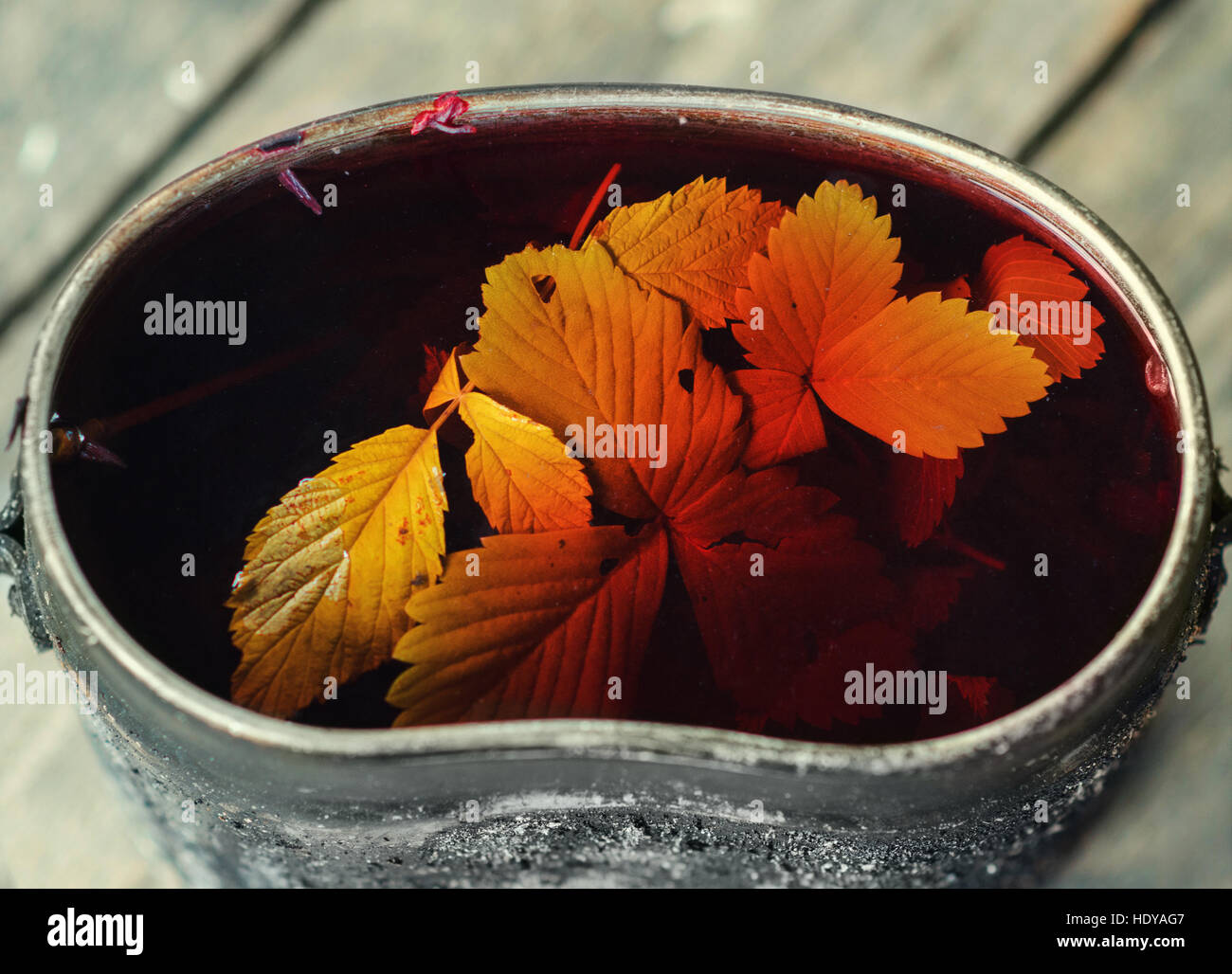 The brewed herbal tea with leaves in the iron bowl. Thermos with warm ...